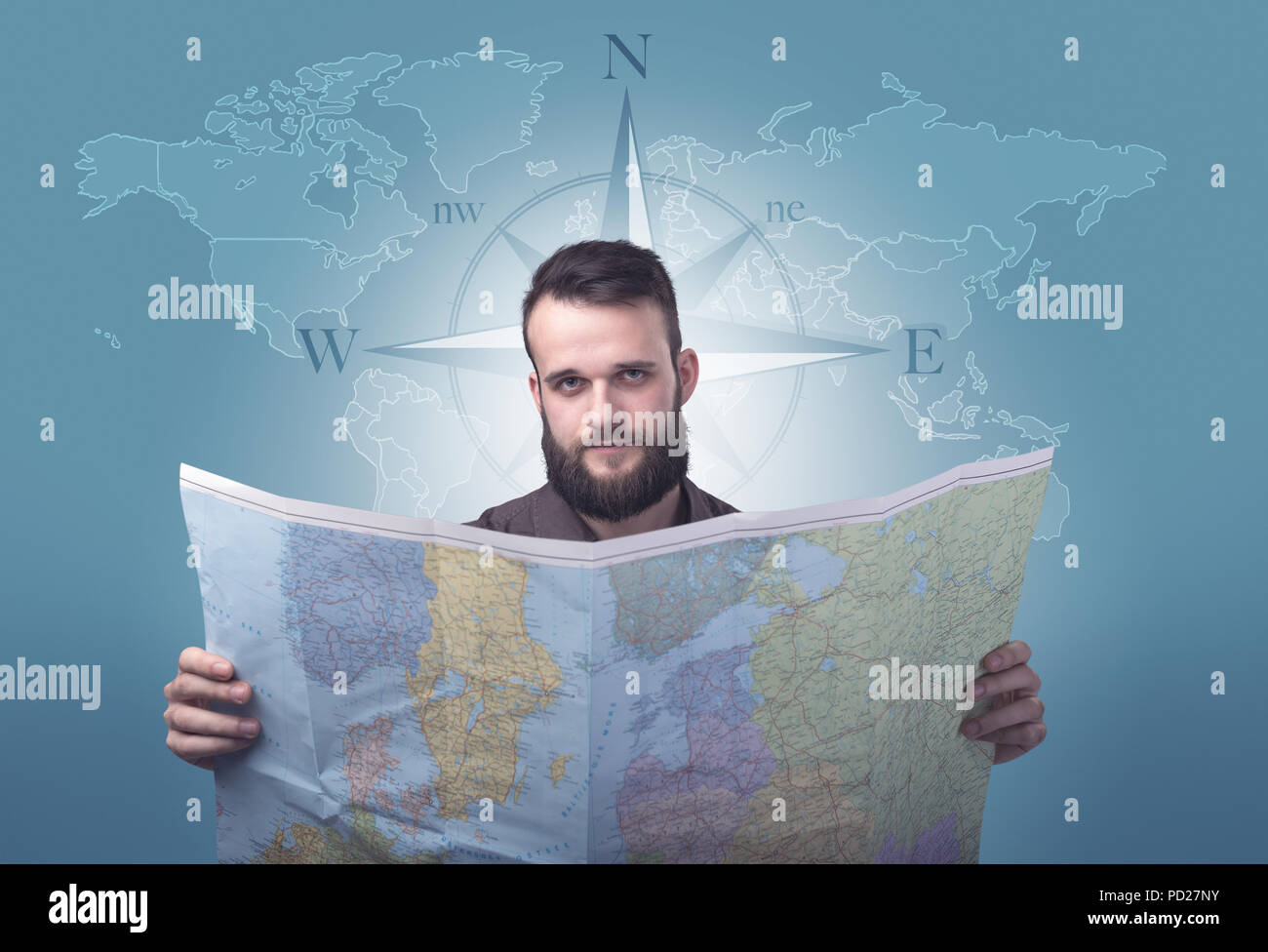 Handsome young man holding a map with a world map and a compass behind ...