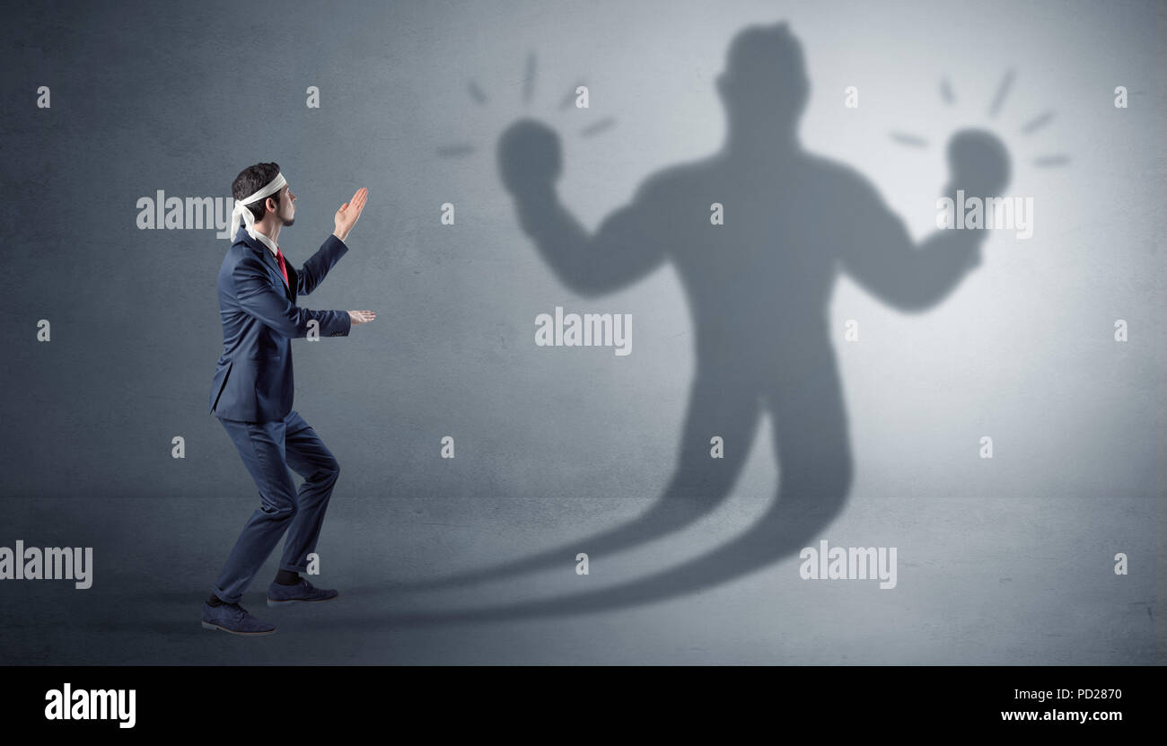 Businessman trying to fight with his unarmed shadow Stock Photo - Alamy