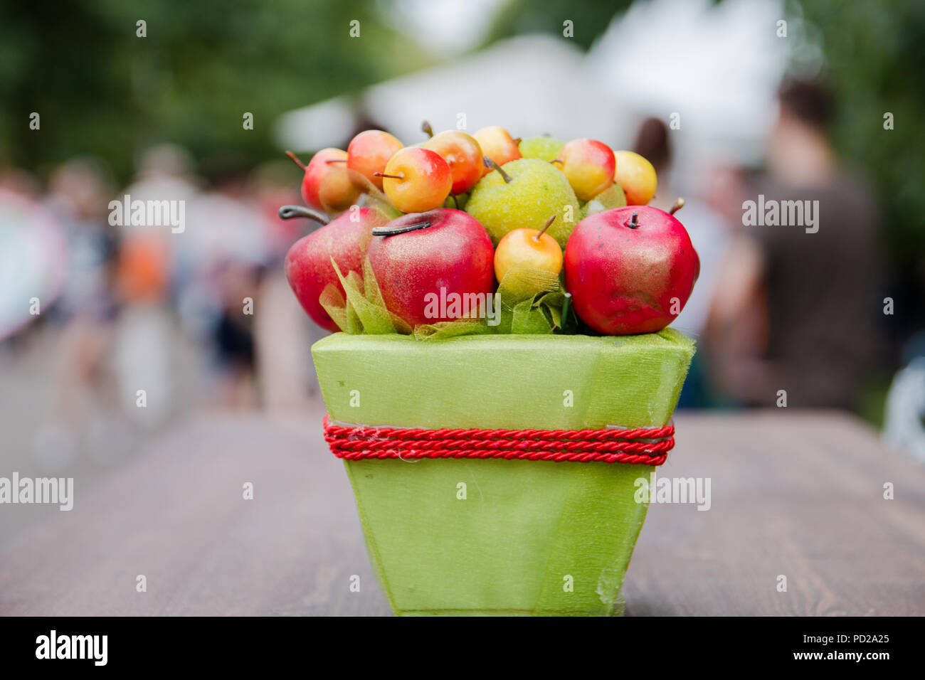 decorative apples in a pot on the background of a blurred crowd of ...