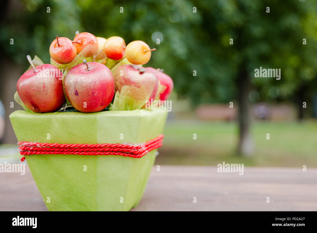 decorative apples in a pot on a green tree background Stock Photo - Alamy