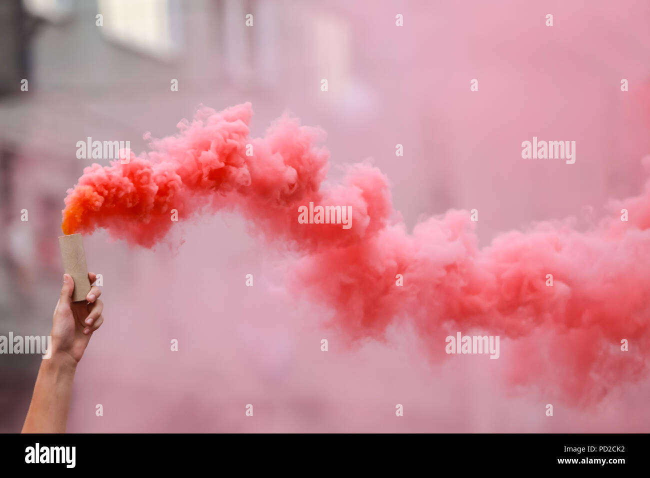 A man holding a hand flare with red smoke Stock Photo - Alamy