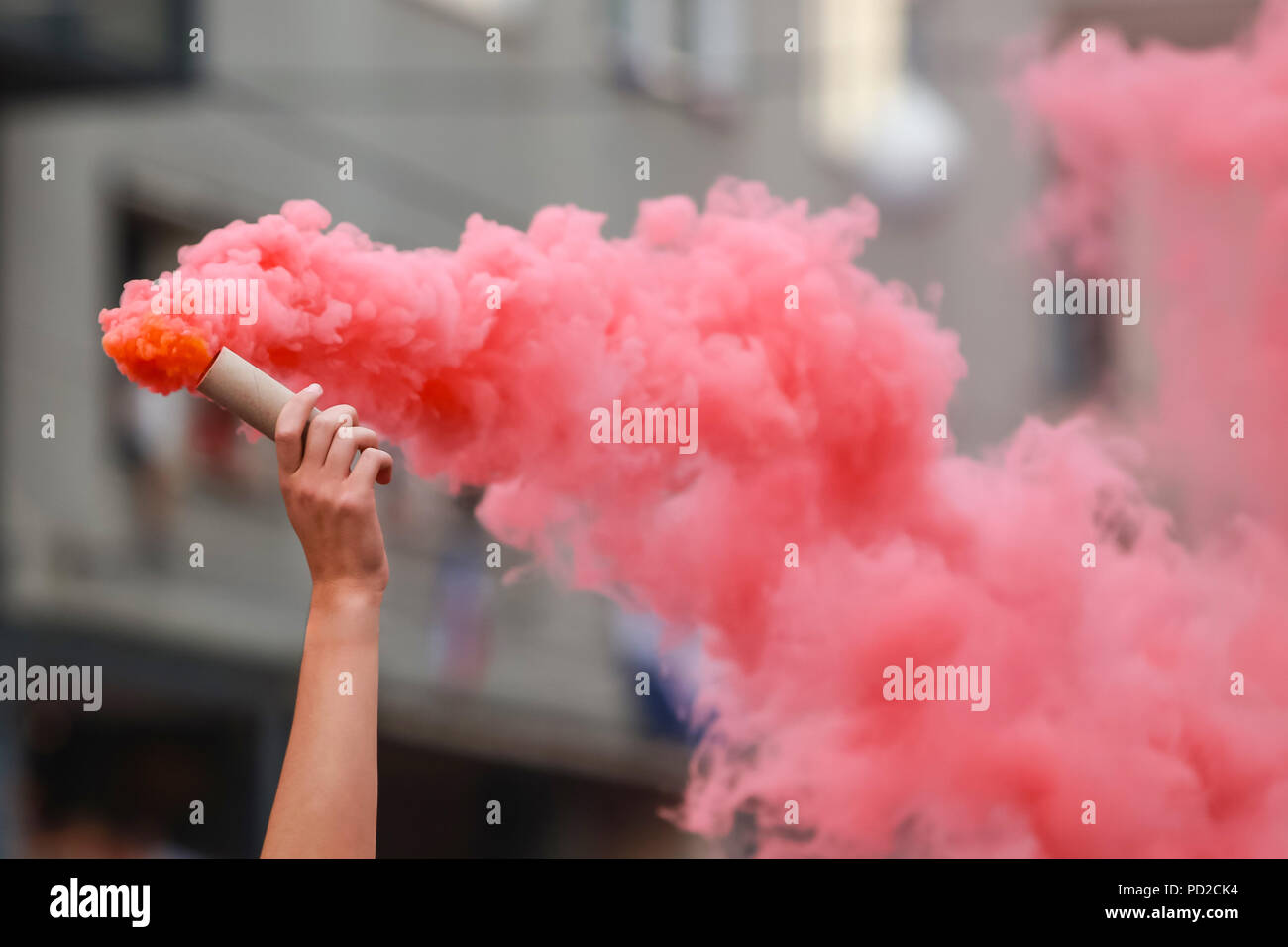 A man holding a hand flare with red smoke Stock Photo - Alamy