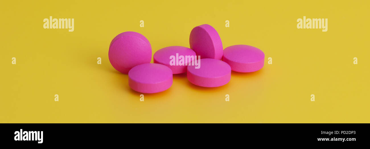 Several large bright pink tablets on a yellow background Stock Photo ...