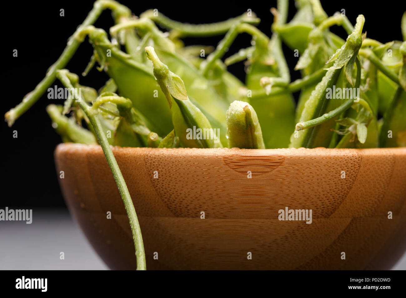 Photo of green pea pods in wooden plate on black background Stock Photo ...