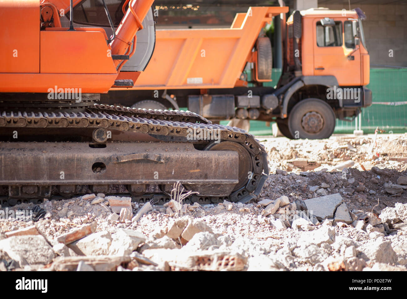 Track excavator and dump truck over loads of brick rubble debris ...