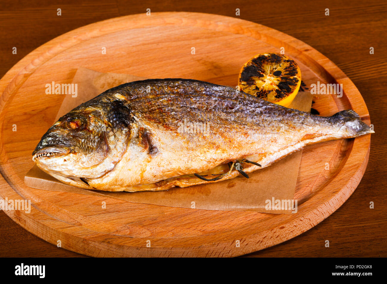 Grilled dorada with lemon over wooden background Stock Photo - Alamy