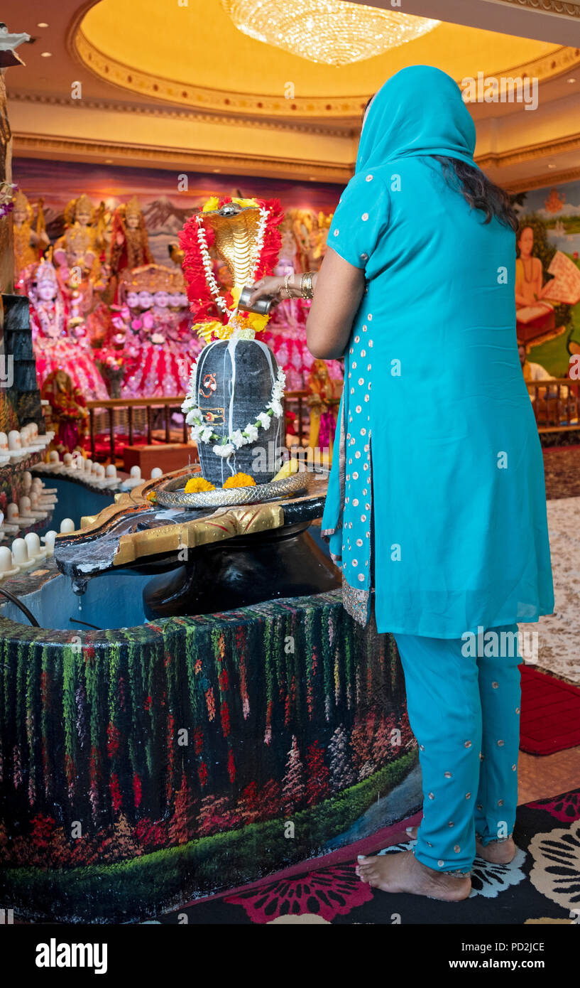 A woman pours milk on the statue of the deity Shiva at a Hindu temple ...