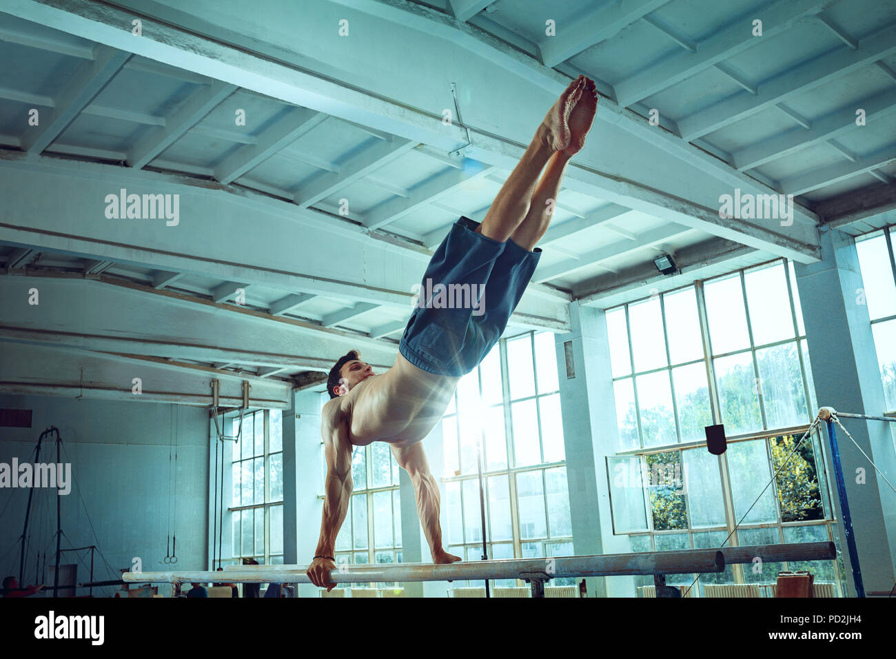 The sportsman performing difficult gymnastic exercise at gym. The sport ...