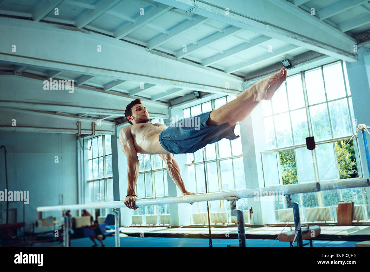 The sportsman performing difficult gymnastic exercise at gym. The sport ...
