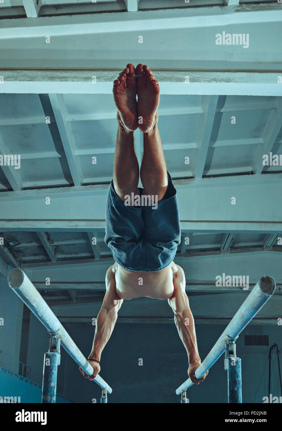 The sportsman performing difficult gymnastic exercise at gym. The sport ...
