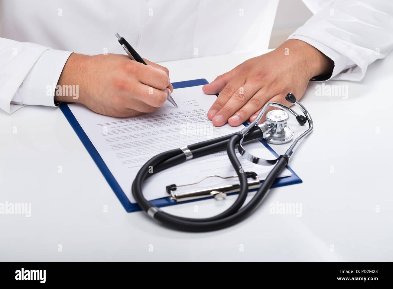Doctor's hand signing document with stethoscope on desk Stock Photo - Alamy