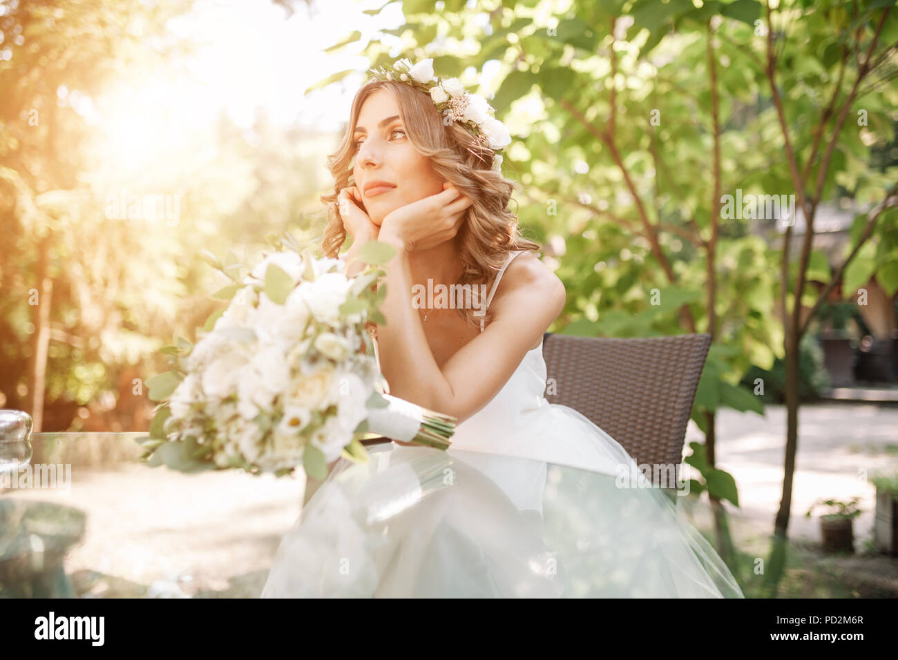a young bride sits at a glass table with her hands folded at the chin ...