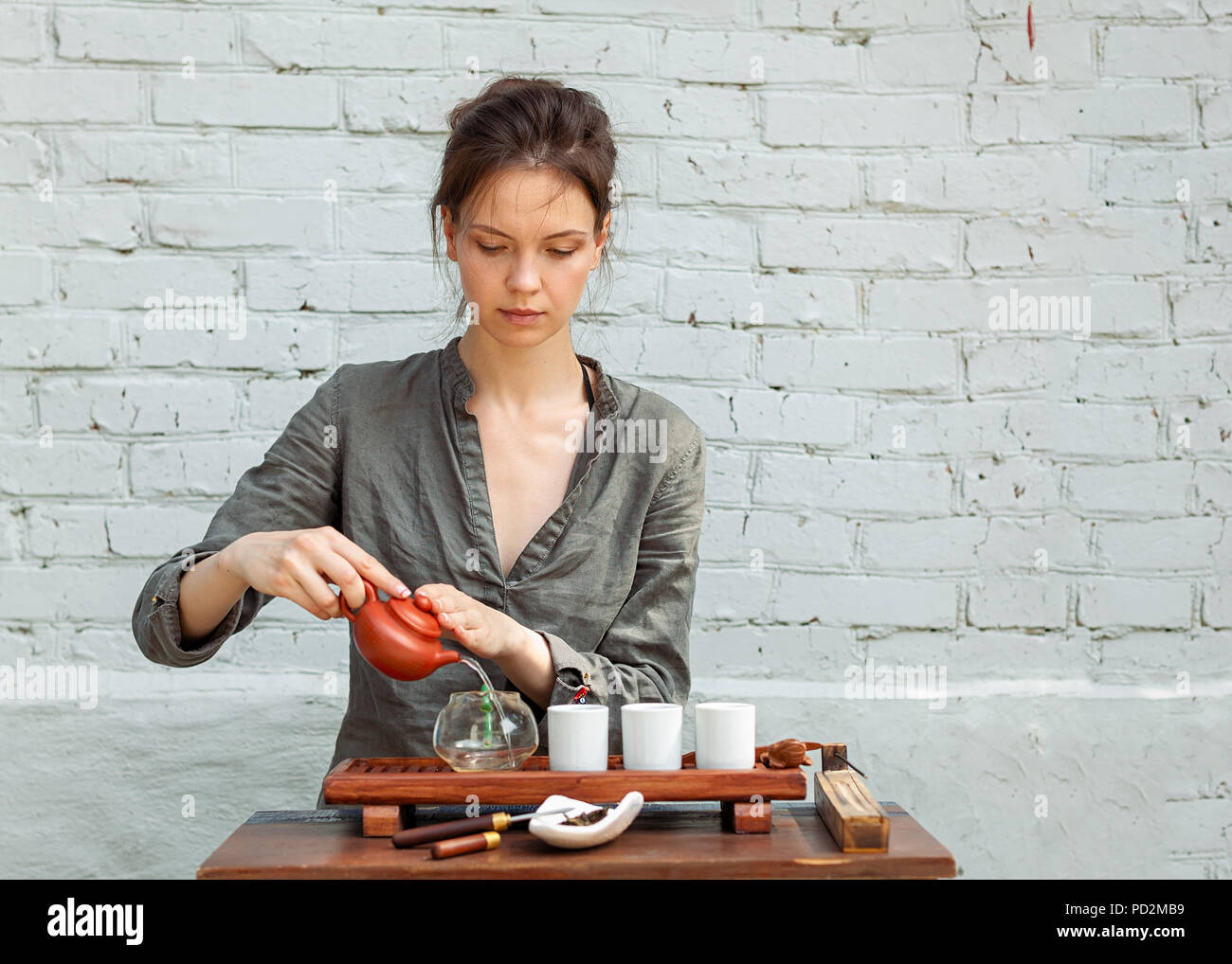 Young woman sitting in meditation pose in front of tea set and aroma ...