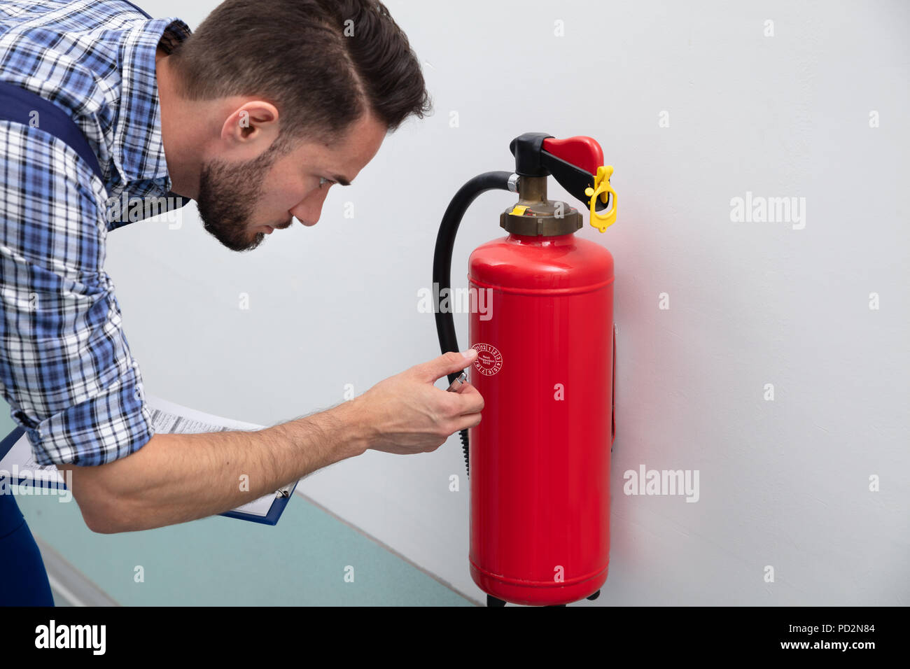 Young Male Technician Checking Symbol On Fire Extinguisher Stock Photo ...