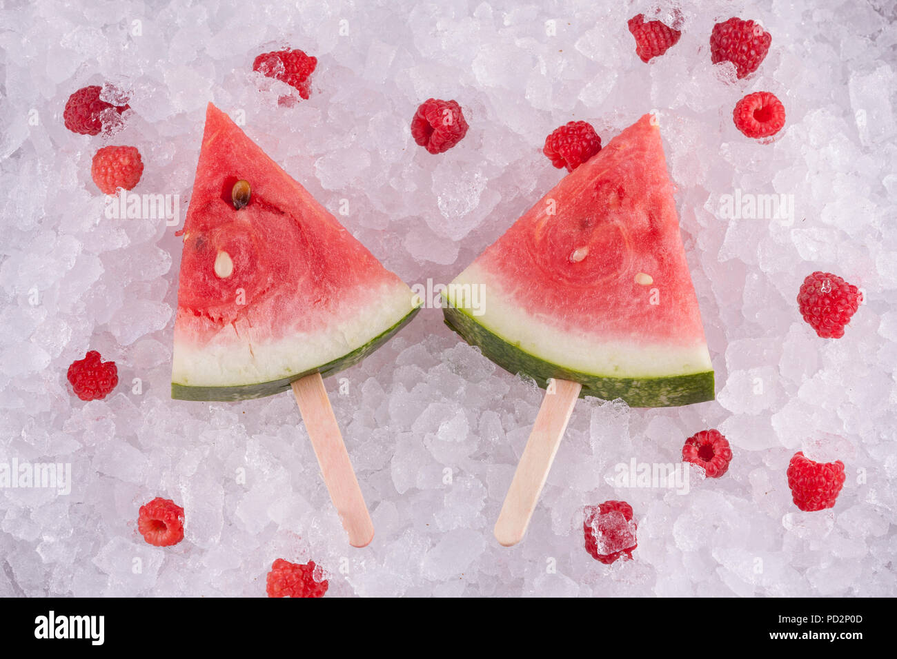 Slices of watermelon on a popsicle stick laid out on ice with ...