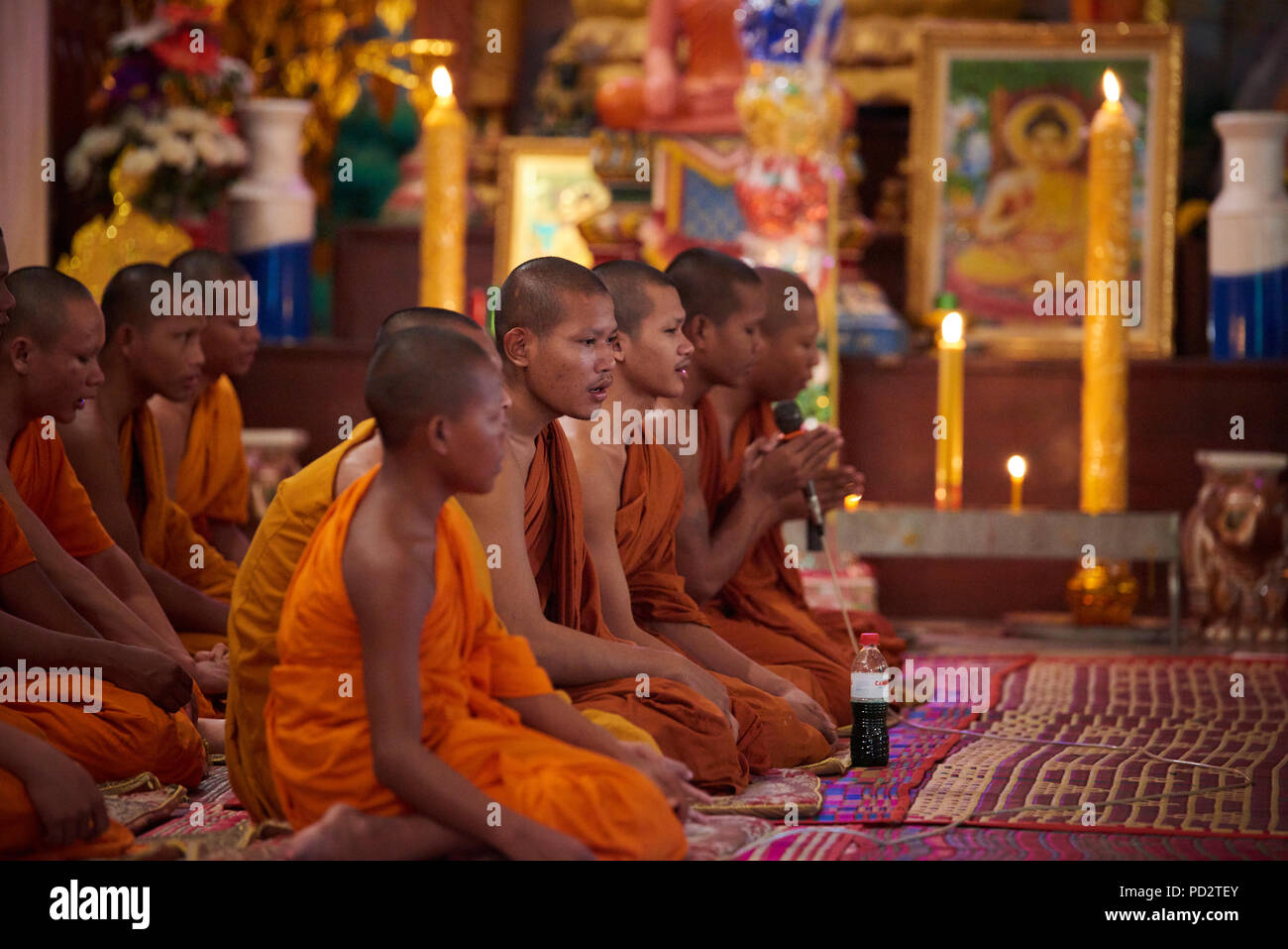A group of young Buddhist monks sitting on the ground during a ceremony ...