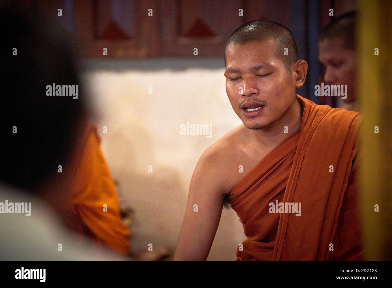 A young Buddhist monk chanting with his eyes closed during a ceremony ...