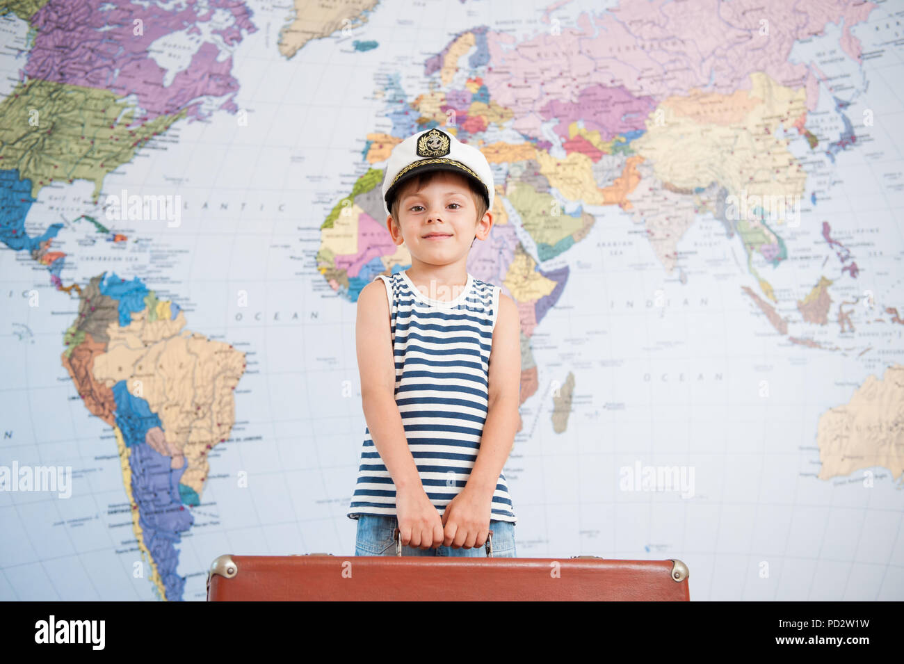 happy smiling caucasian kid in captain cap holding heavy suitcase on ...