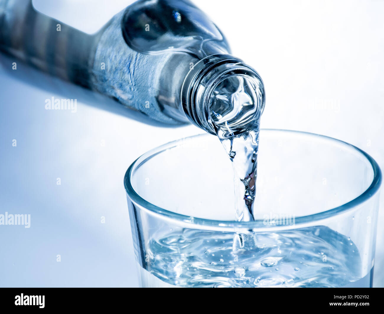 Pouring of cold clear drink water from bottle into glass, close up ...