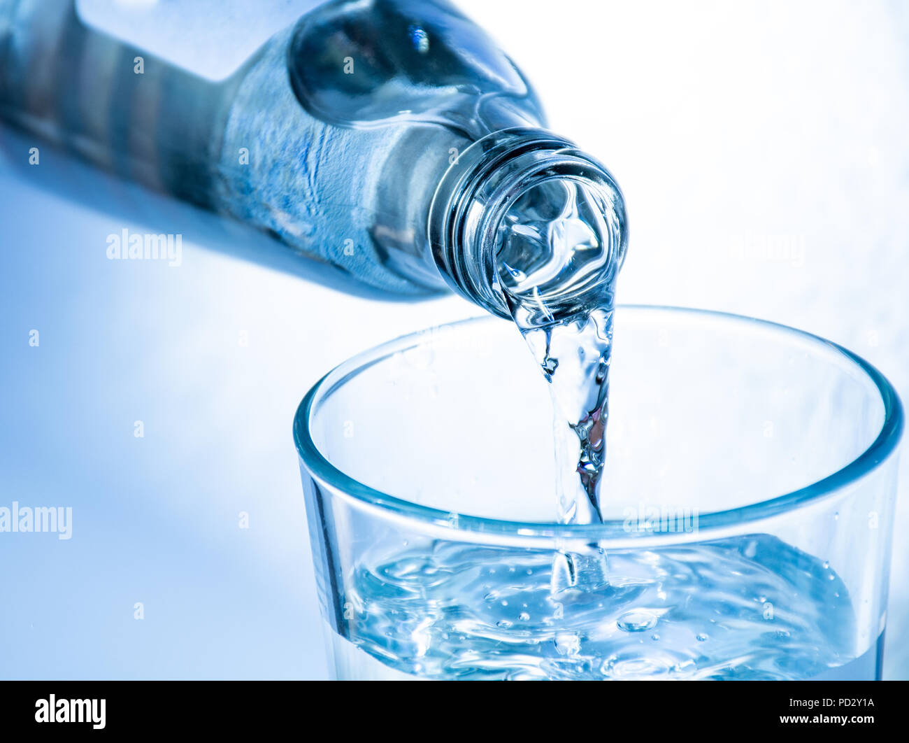 Pouring of cold clear drink water from bottle into glass, close up ...