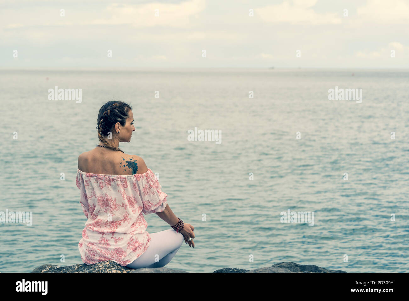 Woman meditating by sea Stock Photo - Alamy