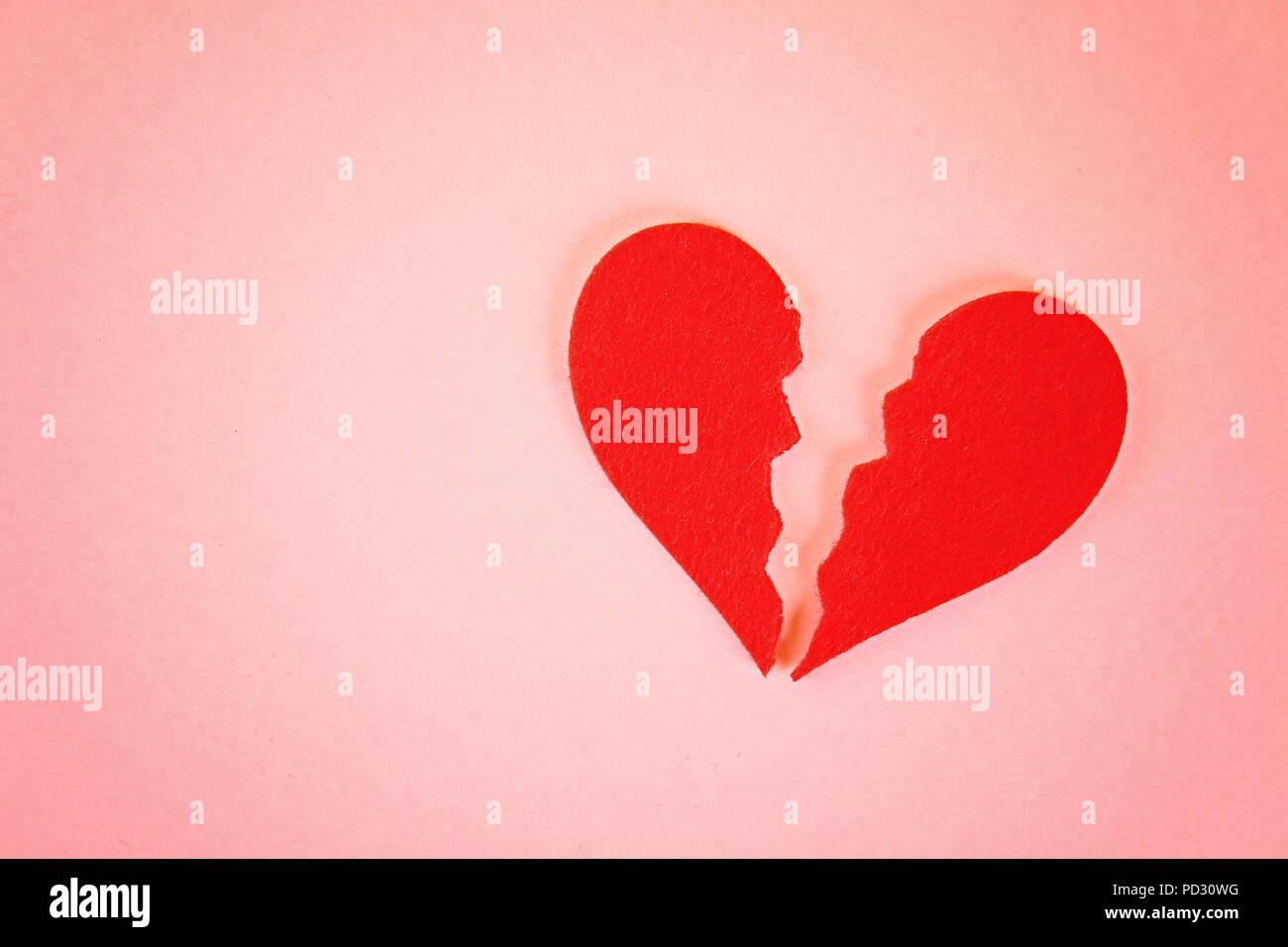 Red felt heart broken into two halves on a pink background Stock Photo ...