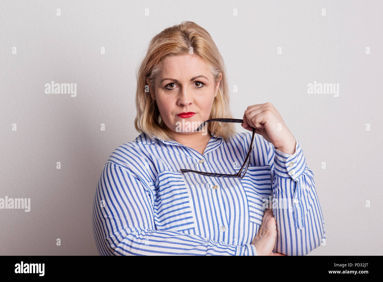 Portrait of an attractive overweight woman with glasses in a studio ...