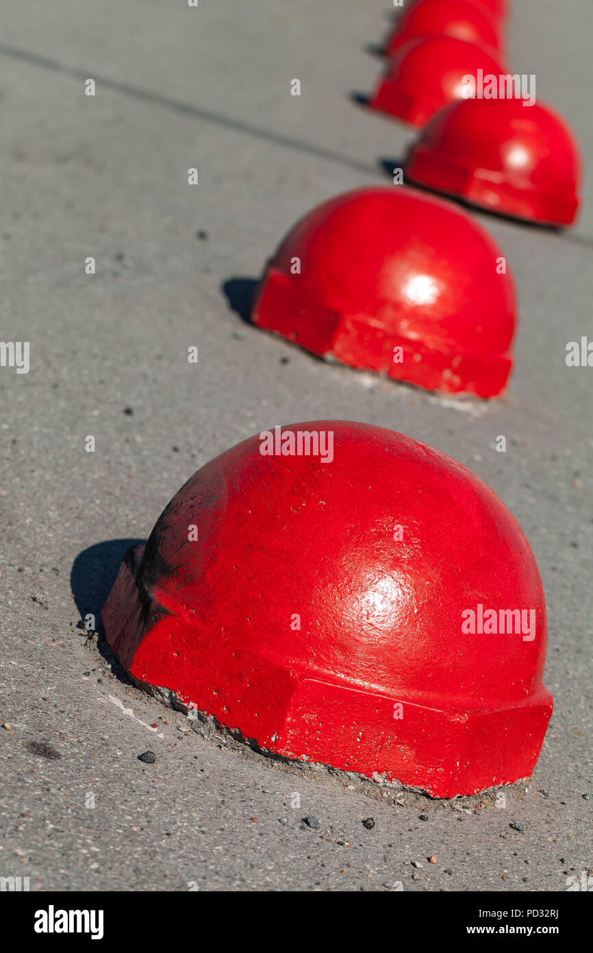 Round red concrete road blocks in a row Stock Photo - Alamy