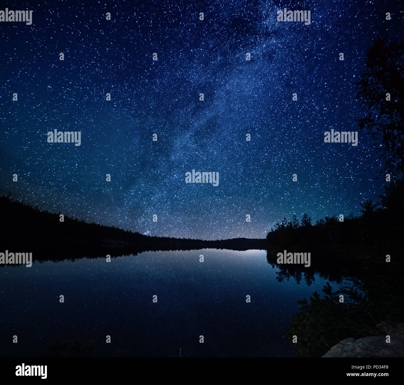 Lake at night with amazing starry sky and reflections in the water ...