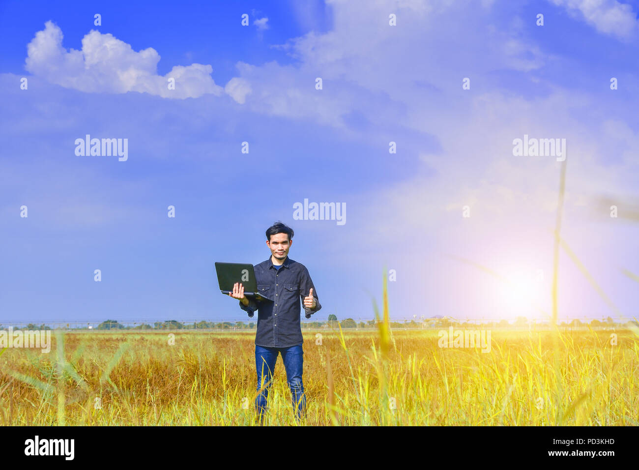 Man holding computer in green field under blue sky.Blogger Sky and ...