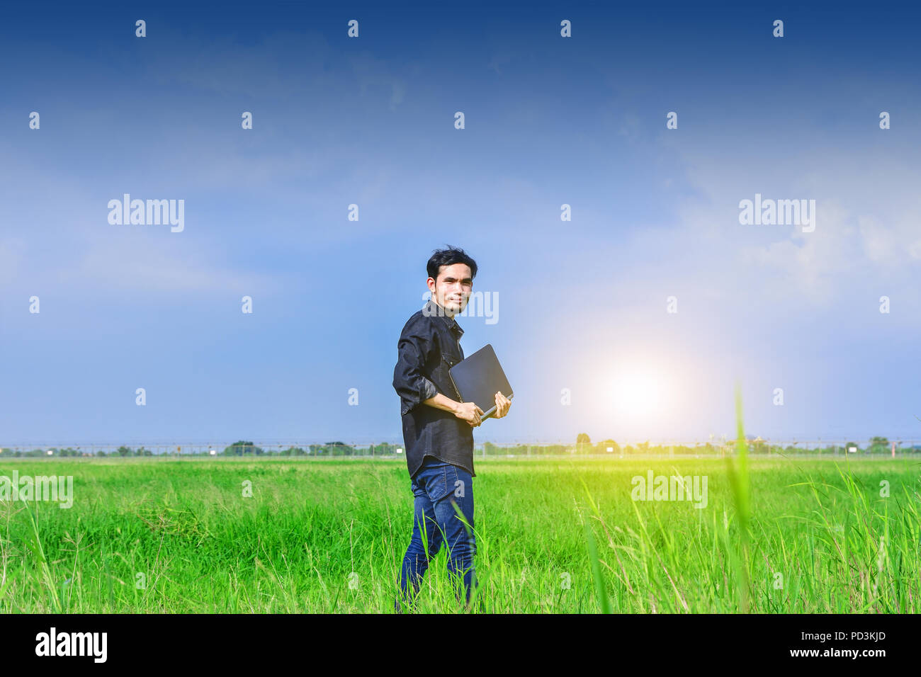 Man holding computer in green field under blue sky.Blogger Sky and ...