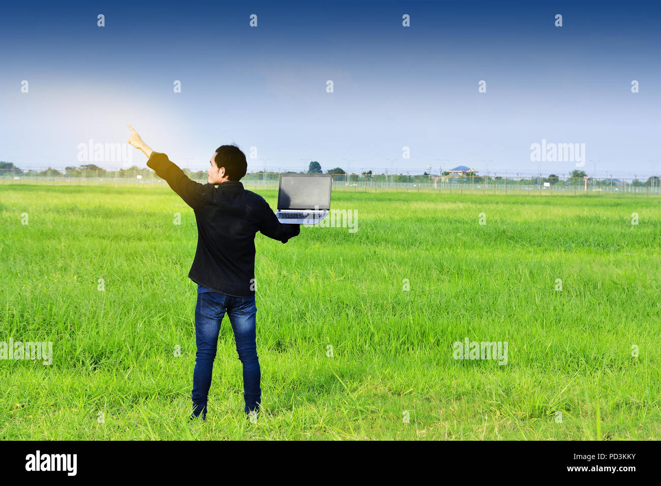 Man holding computer in green field under blue sky.Blogger Sky and ...