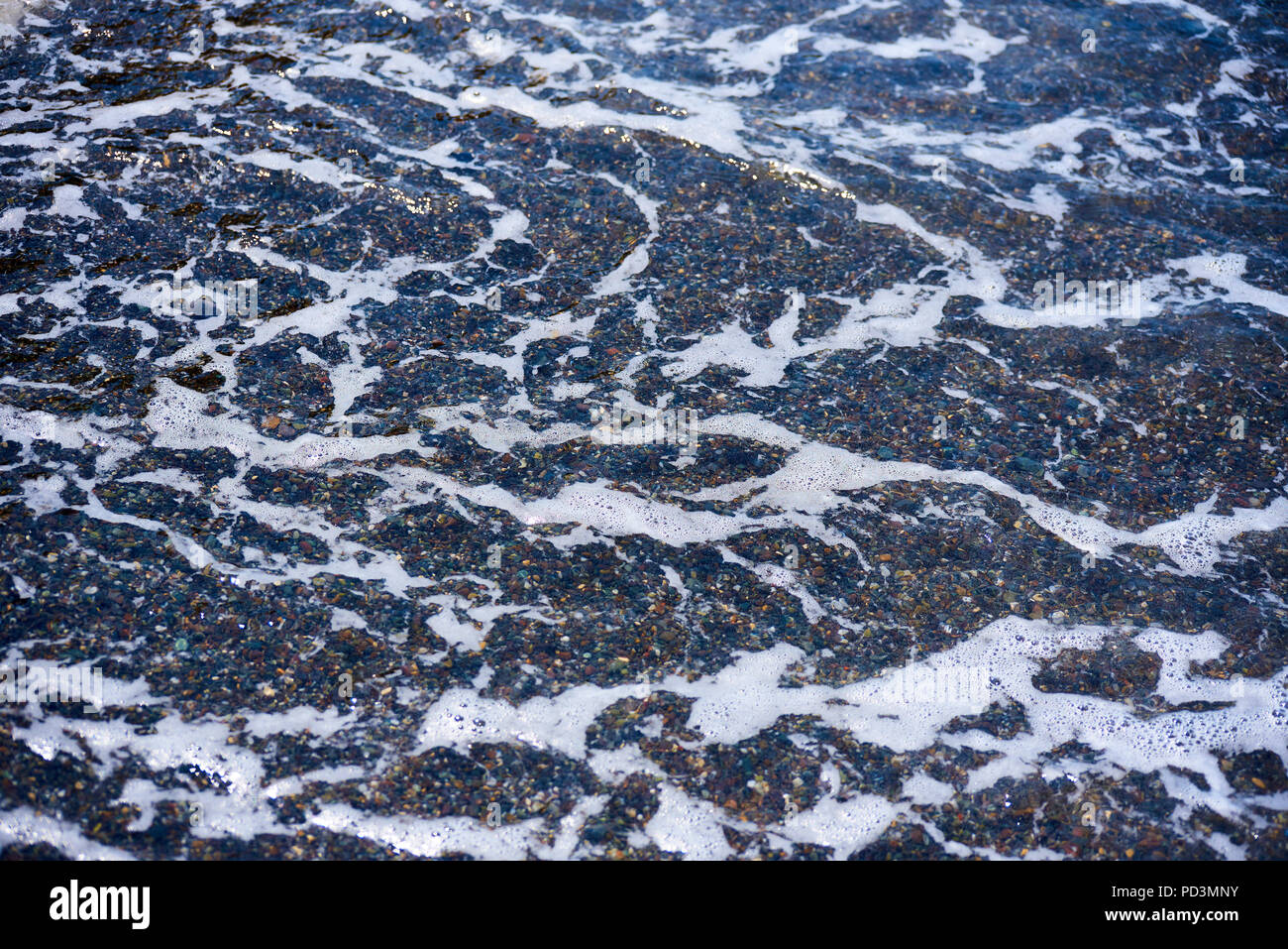 Background, texture sea water with foam and pebbles Stock Photo - Alamy
