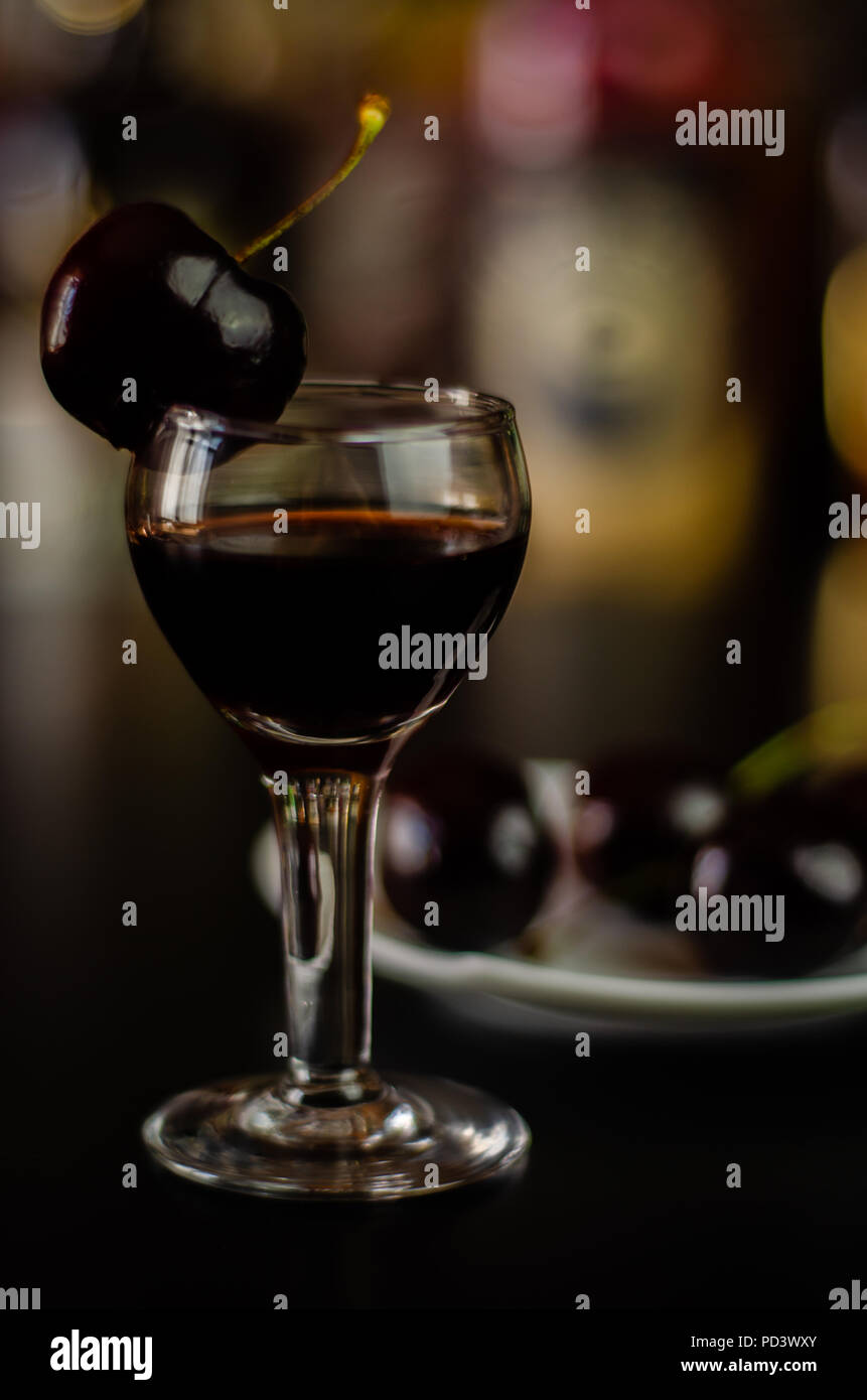 Cherry liqueur and juicy ripe cherries on the table in the bar, an ...