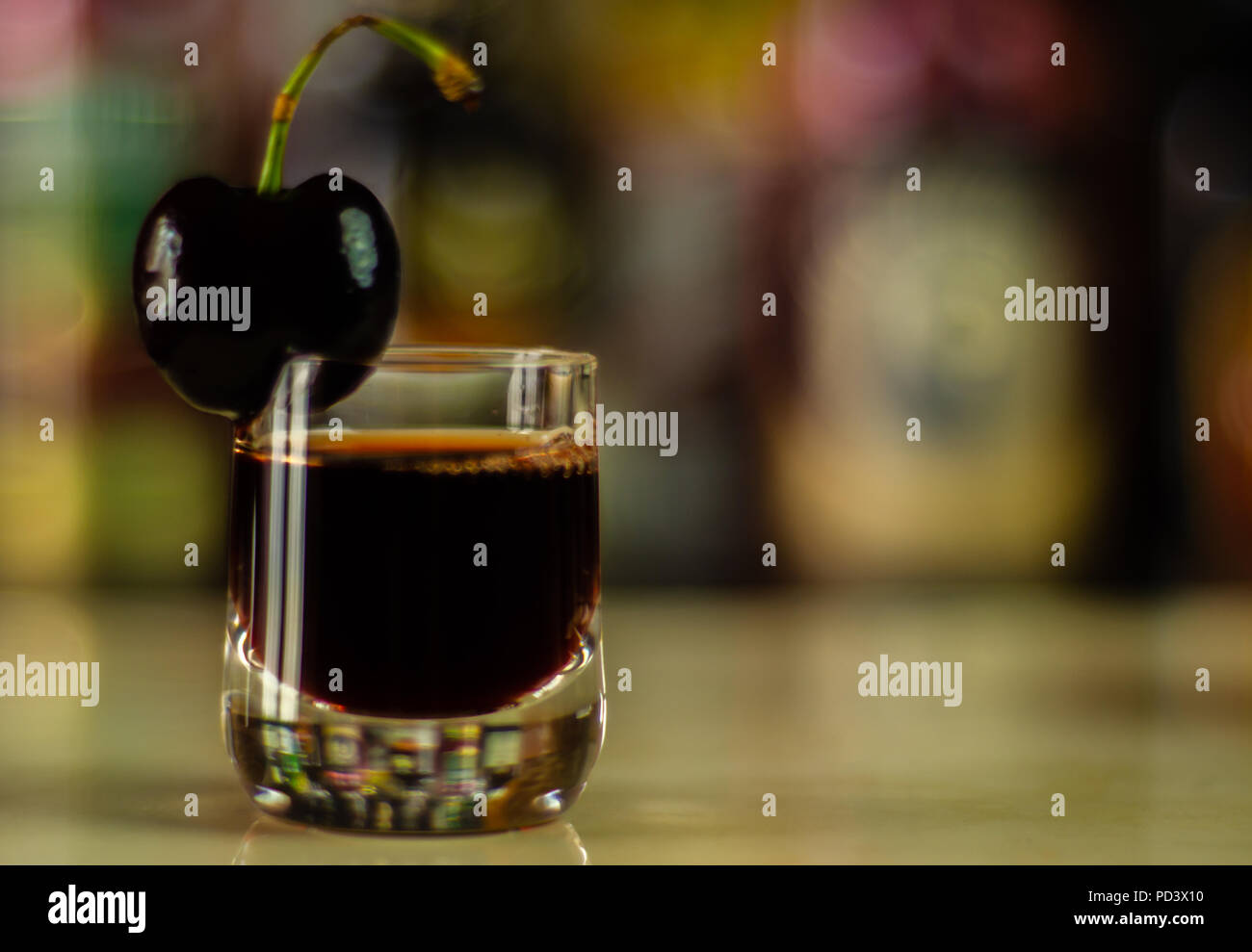 Cherry liqueur and juicy ripe cherries on the table in the bar, an ...