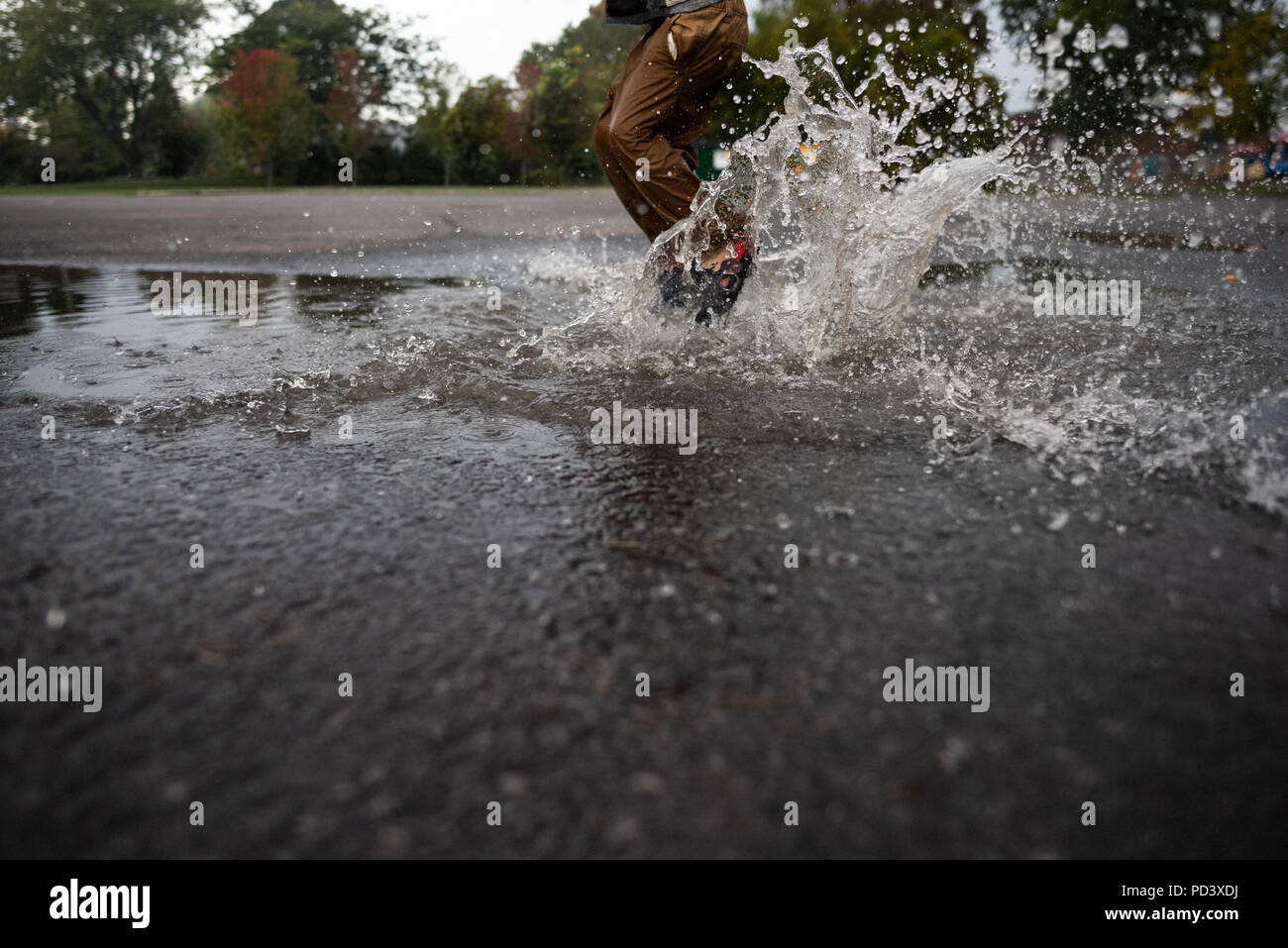 Child splashing in puddle on road Stock Photo - Alamy