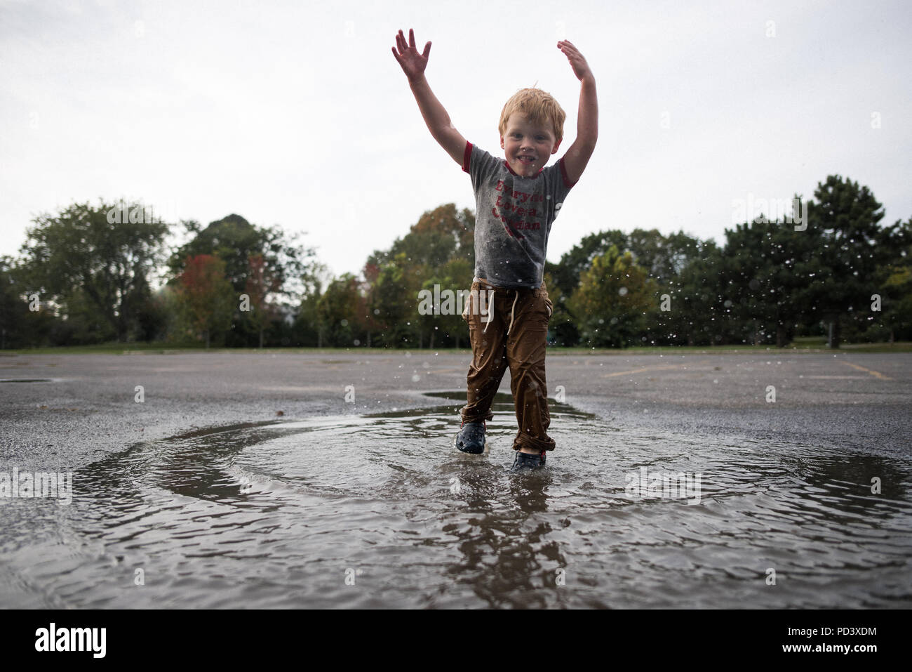 Boy playing in puddle on road Stock Photo - Alamy