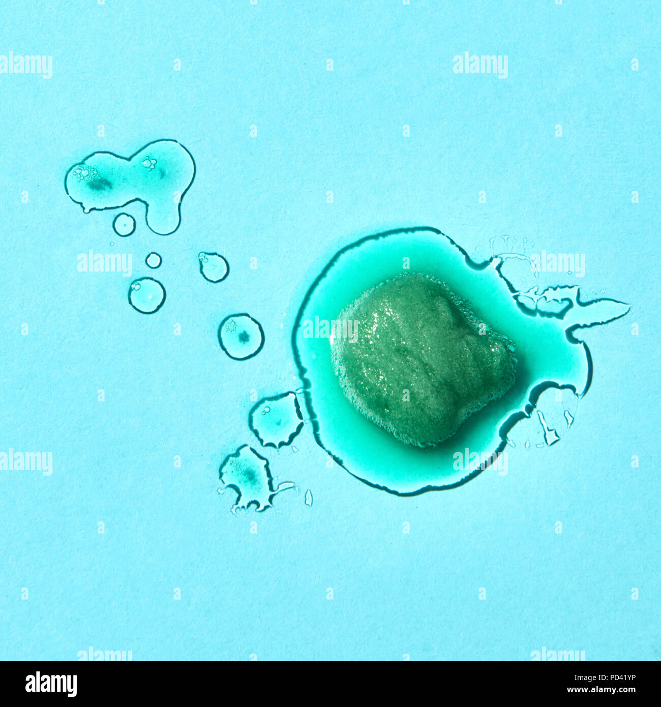 Flat lay of a puddle of melted green mint ice cream on a blue glass ...