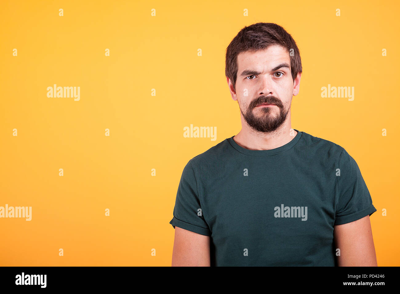 Grumpy stressed worried man on yellow background lookin at the camera ...