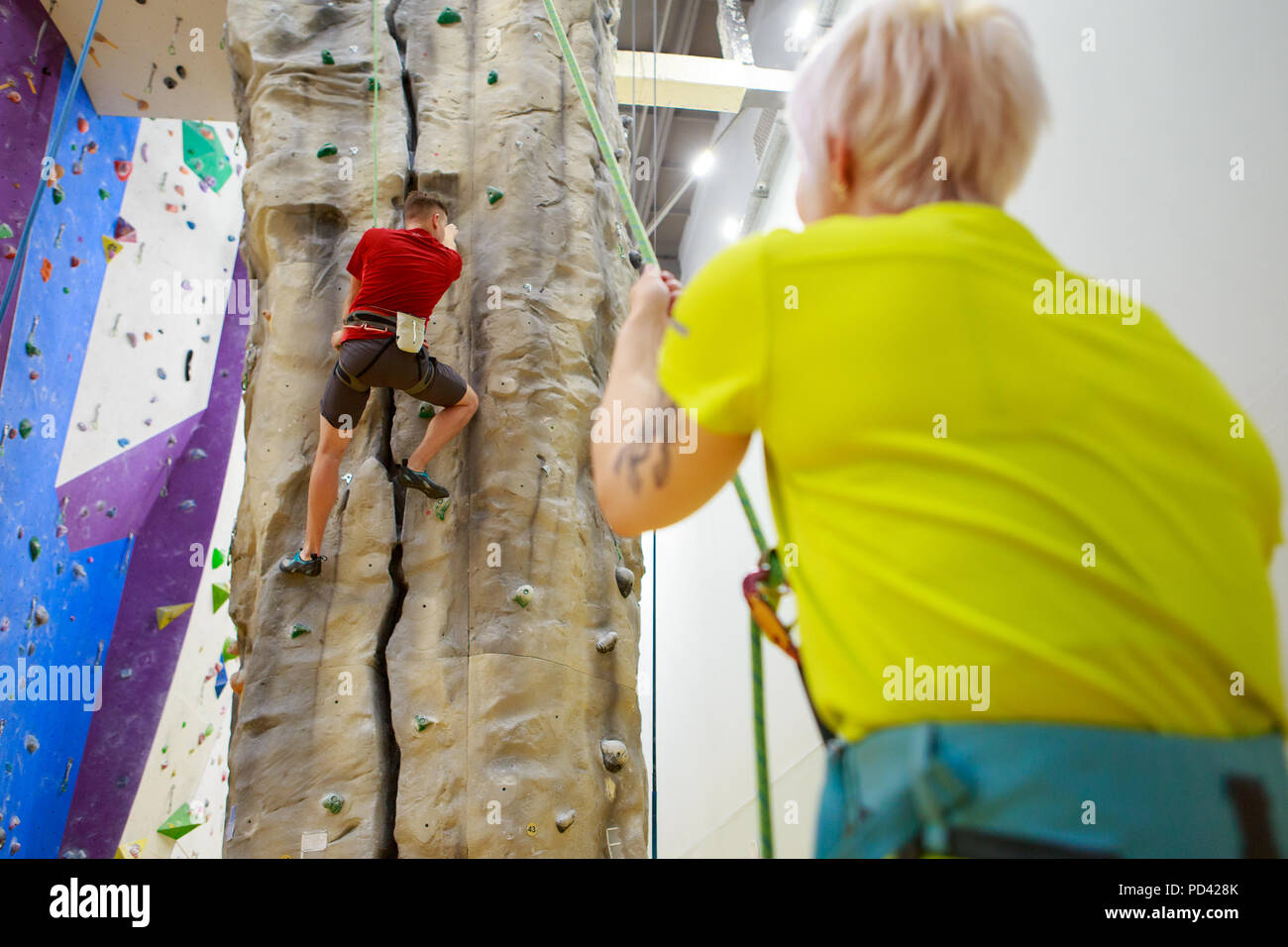 Photo from back of man climbing on wall and female trainer Stock Photo ...