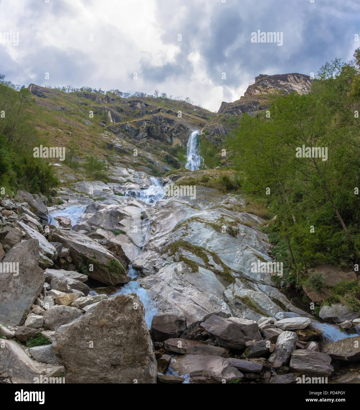 Beautiful small waterfall in the Himalayas on a cloudy spring day ...