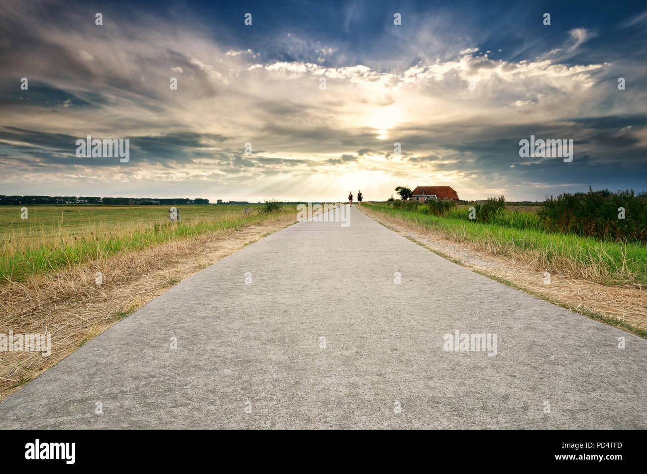 couple walking on path over dramatic sky in summer Stock Photo - Alamy