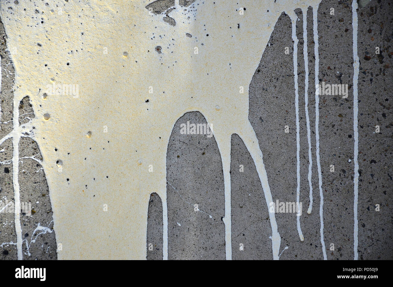 A photograph of a close-up of black paint spots on a concrete wall ...