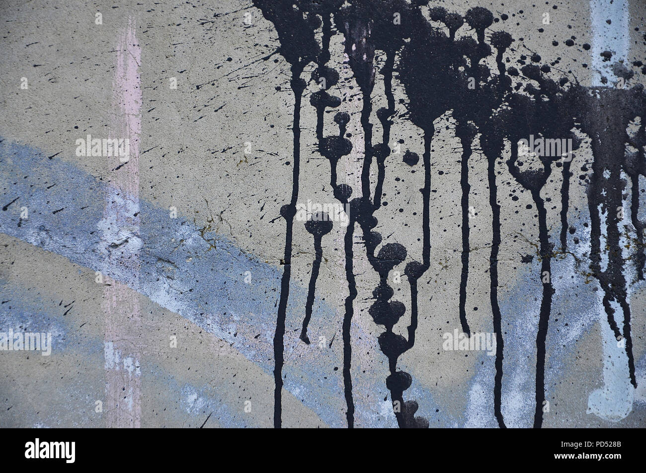 A photograph of a close-up of black paint spots on a concrete wall ...