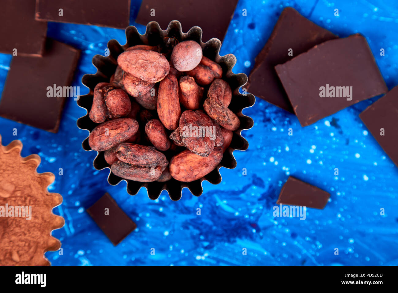 Cocoa beans background on blue table. Dark chocolate pieces and crushed ...
