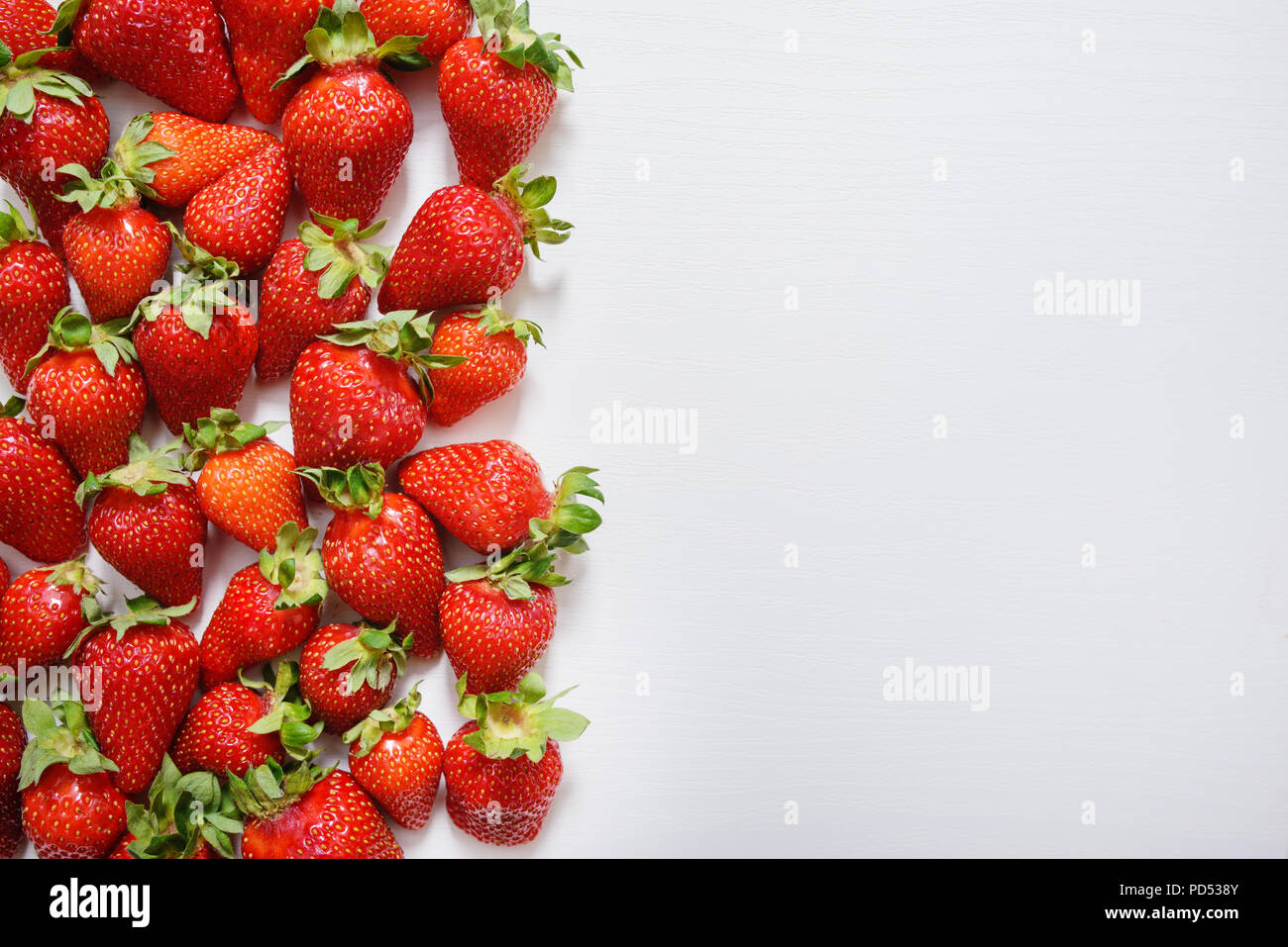 strawberry fruits on the left side on wooden background with copy space ...