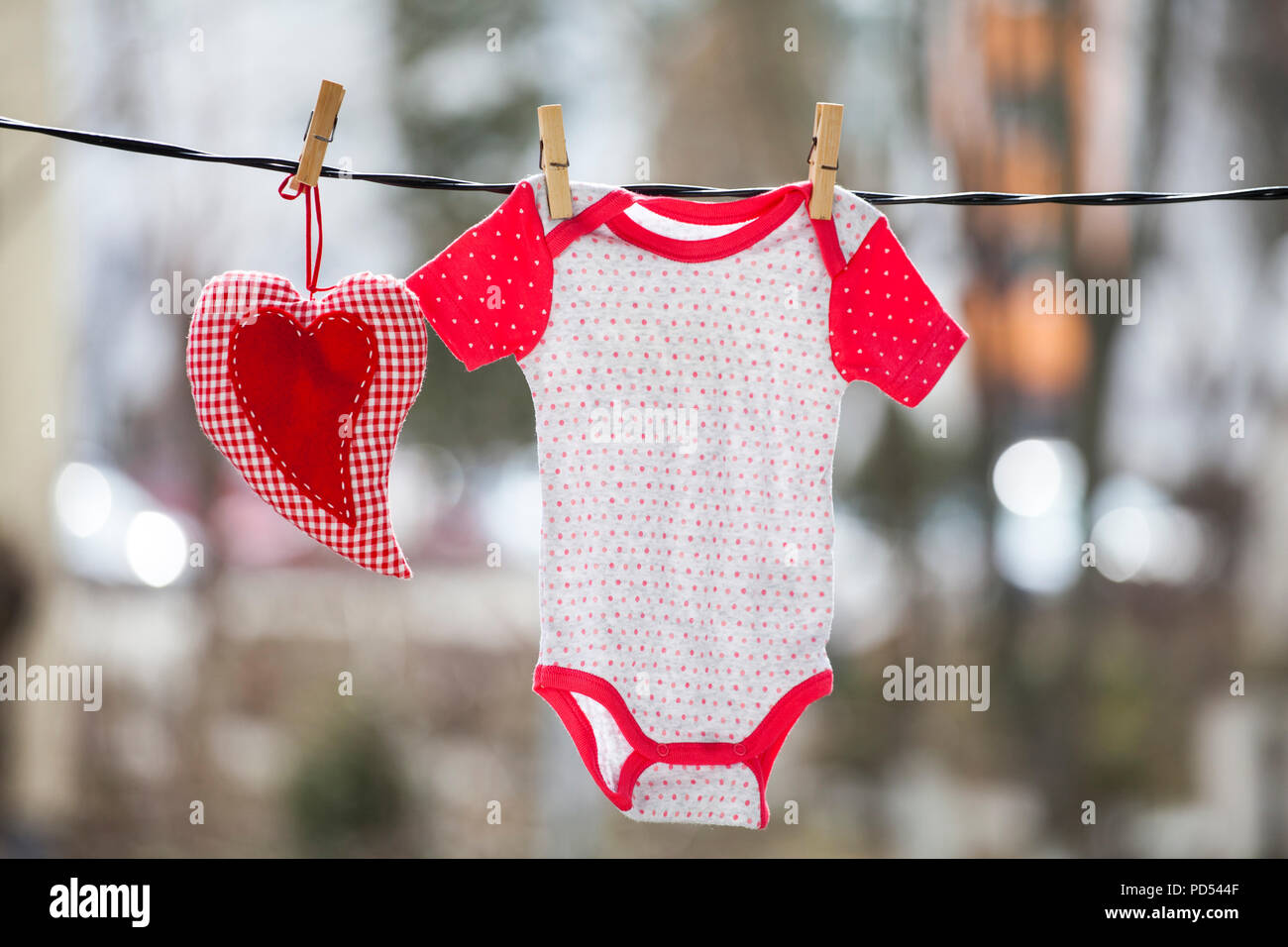 Baby clothes and a red heart hanging on the clothesline Stock Photo - Alamy