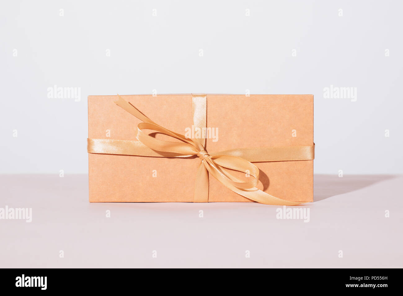 Brown cardboard gift box with beige satin ribbon on table on a white ...