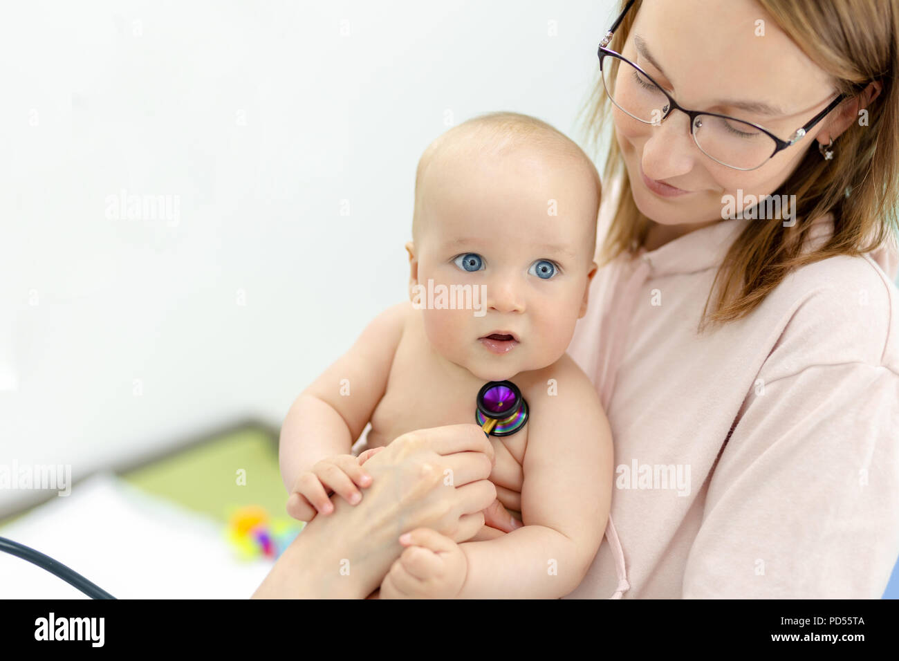 Monther holding baby on hands at doctors office. Pediatrician making ...
