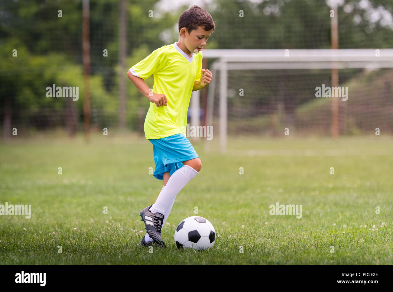 Boy kicking football on the sports field during soccer match Stock ...